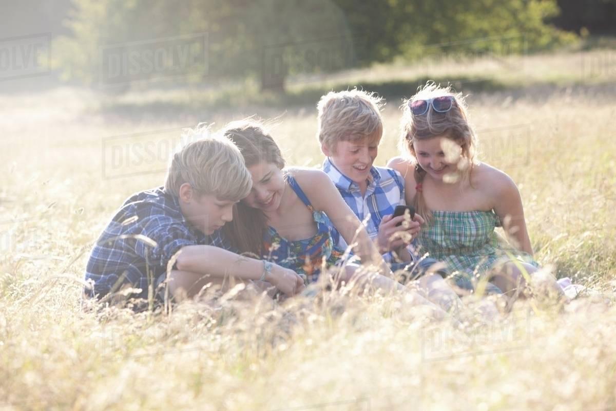 Children using cell phones in field - Stock Photo - Dissolve