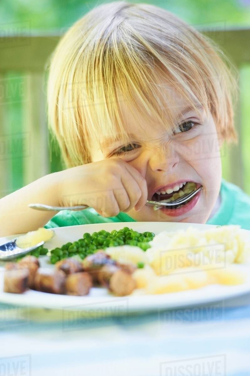 Boy eating vegetables at dinner - Stock Photo - Dissolve