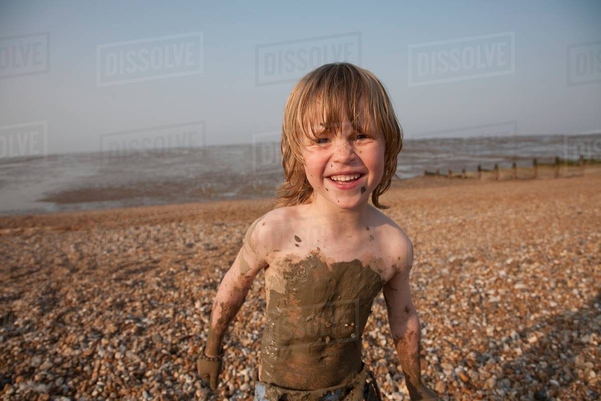 Smiling boy covered in mud at beach - Royalty-free Stock Photo | Dissolve