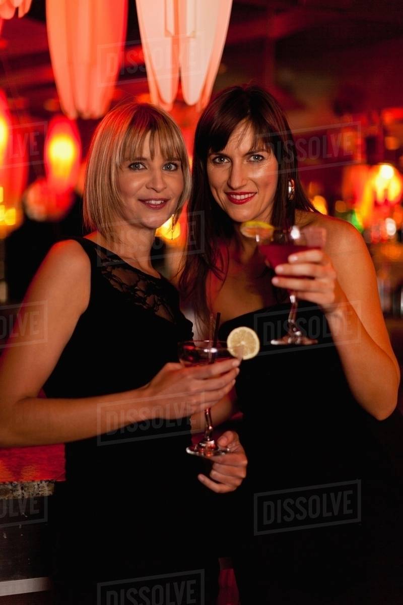 Smiling women having cocktails in bar - Stock Photo - Dissolve