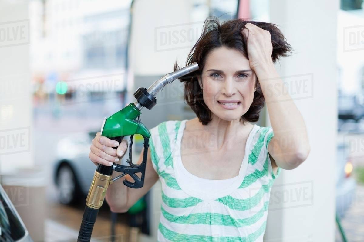 Frustrated woman pumping gas into hair - Stock Photo - Dissolve