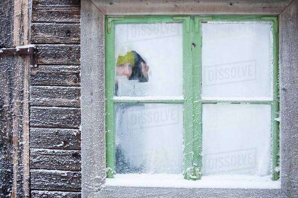 Woman peering out frosty window - Stock Photo - Dissolve