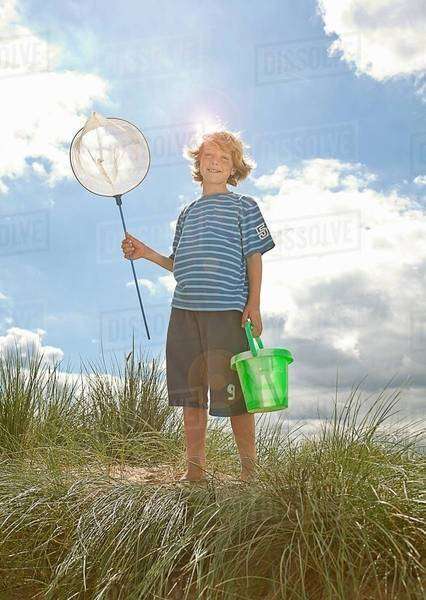 Boy carrying net and pail outdoors - Stock Photo - Dissolve