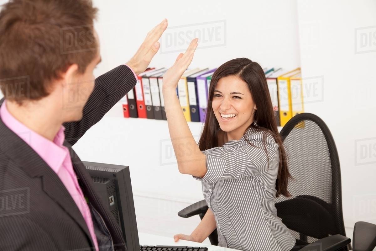 Business people high fiving in office - Stock Photo - Dissolve