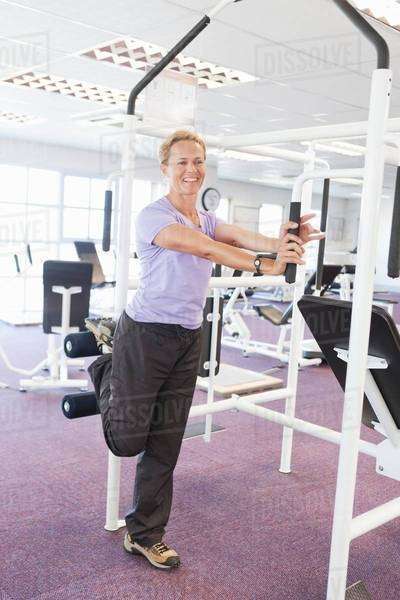 Woman using weights machine in gym - Stock Photo - Dissolve