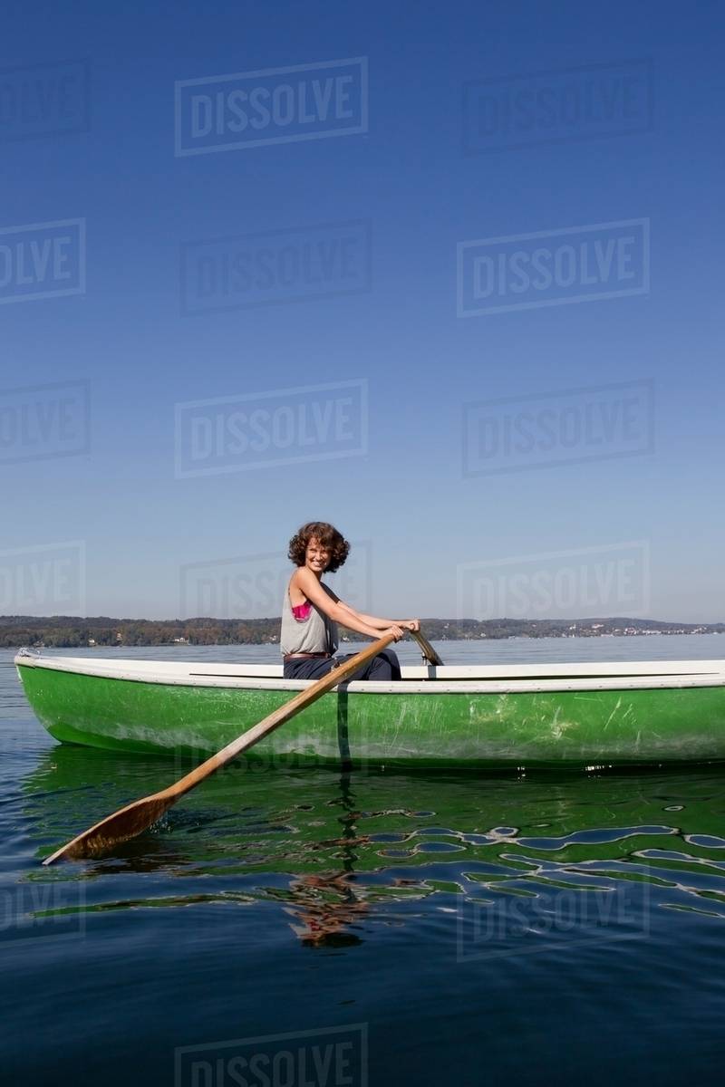 Woman rowing boat in still lake - Royalty-free Stock Photo | Dissolve
