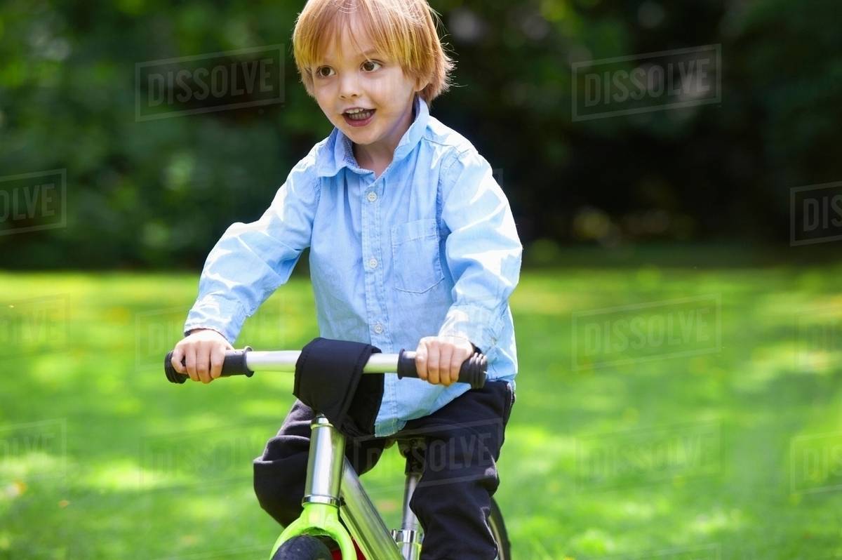 Boy riding bicycle in backyard - Stock Photo - Dissolve