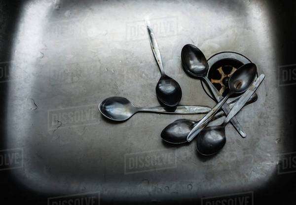 Pile of dirty spoons in sink - Stock Photo - Dissolve