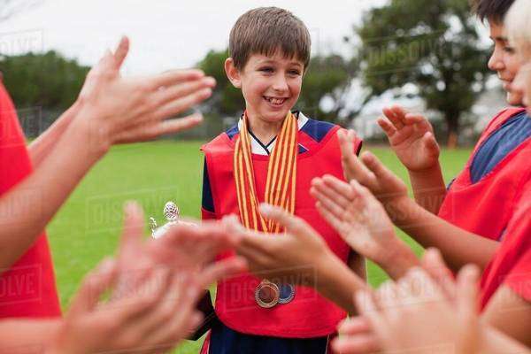 Children cheering teammate with trophy - Stock Photo - Dissolve
