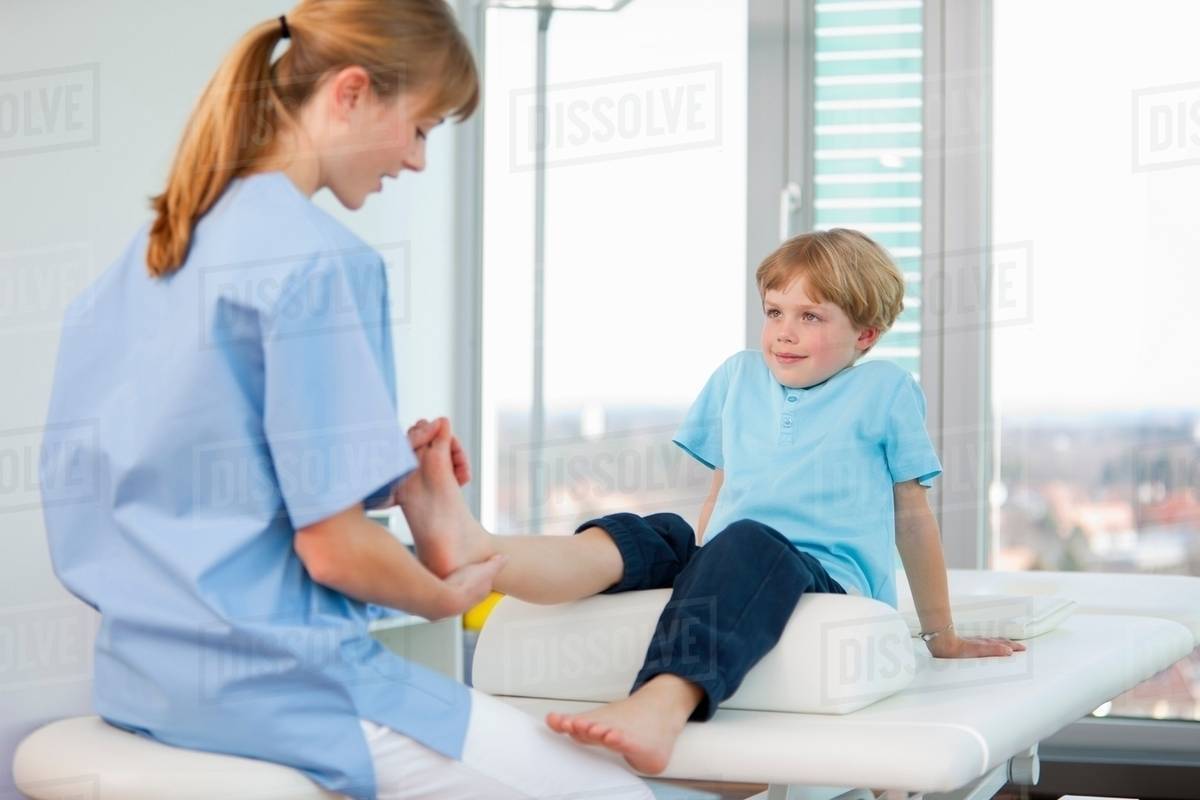 Doctor examining boys feet in office - Royalty-free Stock Photo | Dissolve