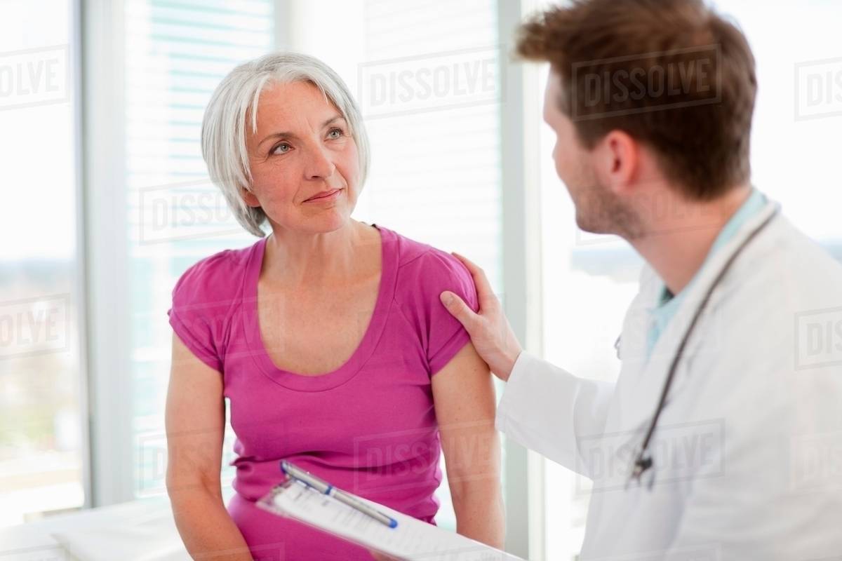 Doctor talking to woman in office - Royalty-free Stock Photo | Dissolve