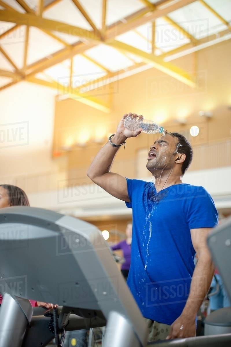 Man pouring water on himself in gym - Stock Photo - Dissolve