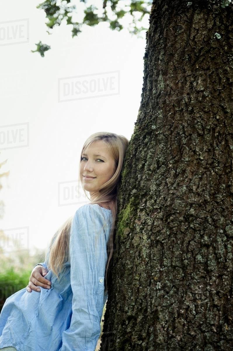 Woman leaning against tree outdoors - Stock Photo - Dissolve