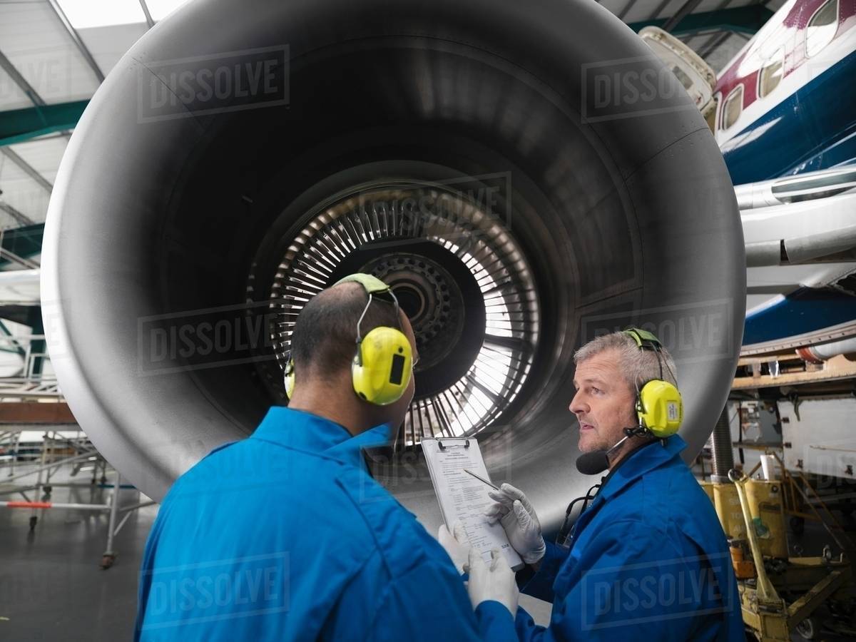 Aircraft engineers wearing ear defenders and working on 737 jet engine ...