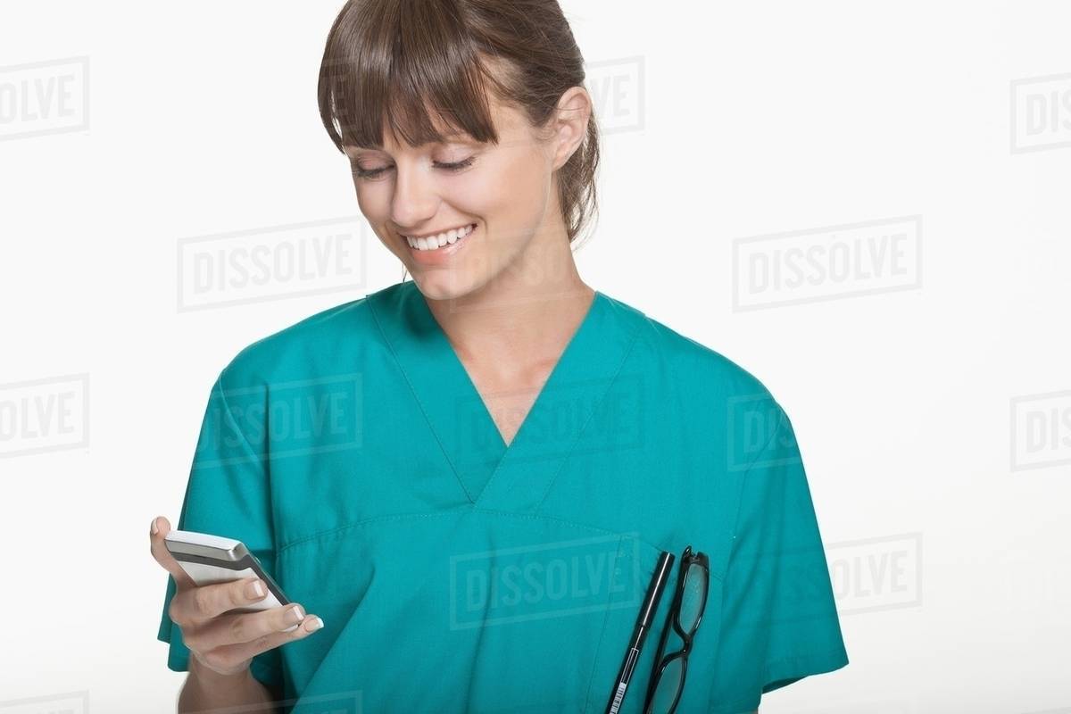 Smiling surgeon using cell phone - Stock Photo - Dissolve