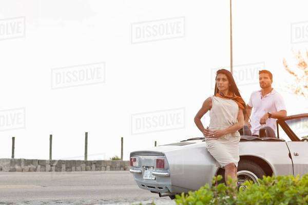 Mid adult couple standing by convertible car by side of road - Stock ...