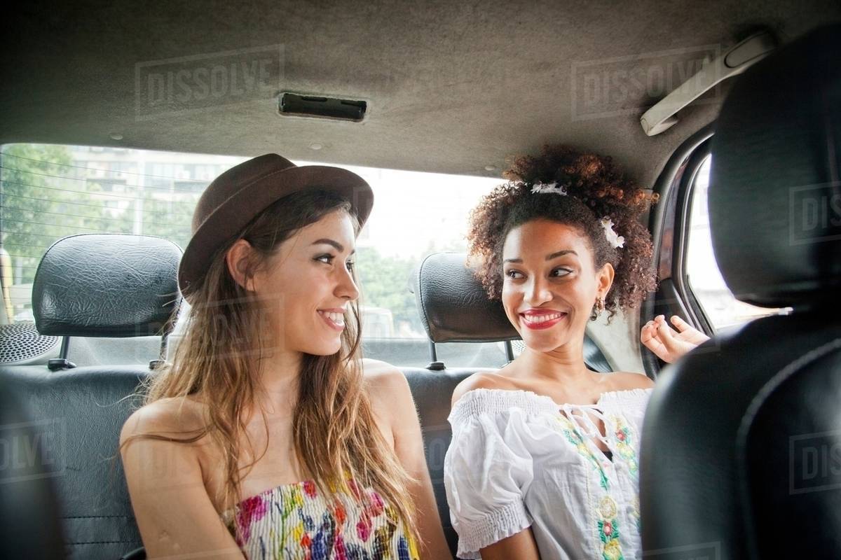Two young women in back of car, smiling - Stock Photo - Dissolve