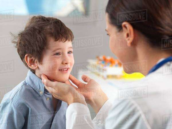 Doctor checking glands of young boy in clinic - Royalty-free Stock ...