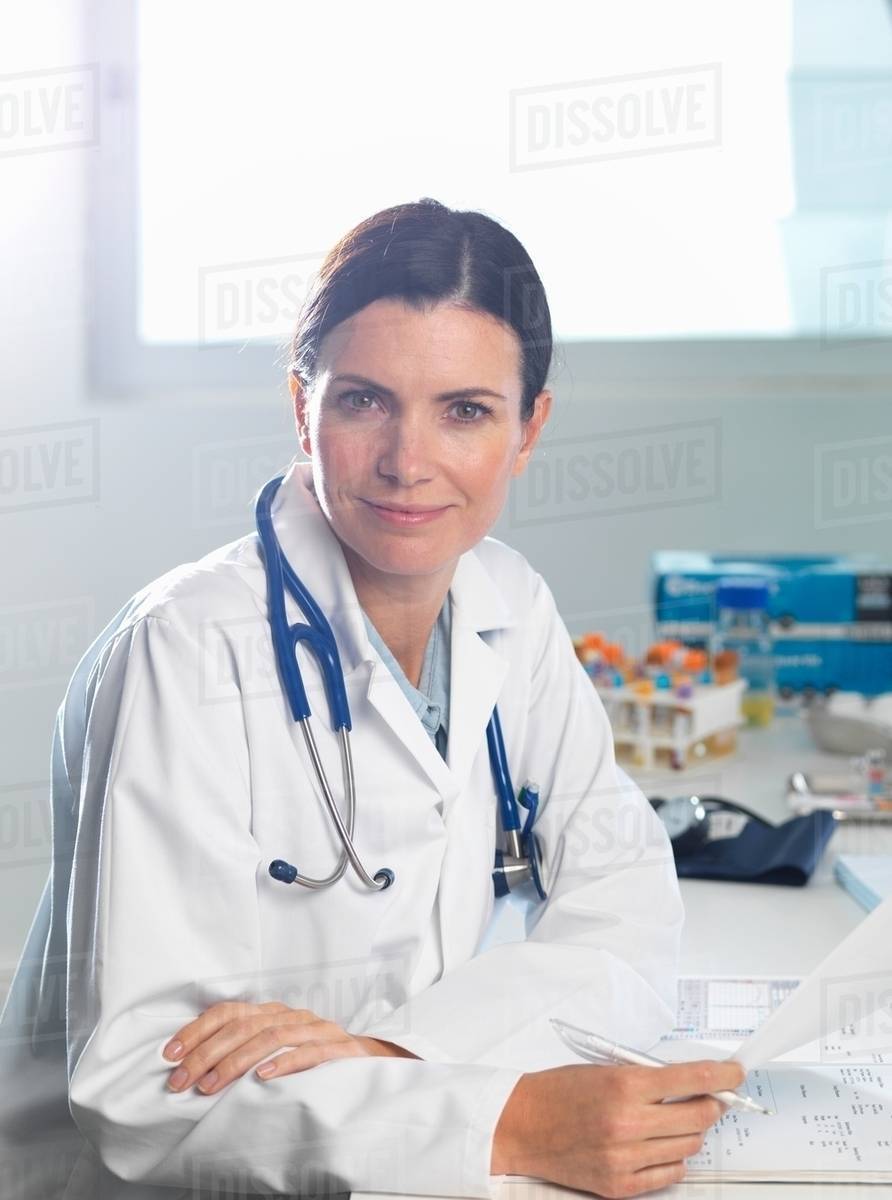 Doctor at desk reviewing patient's notes - Stock Photo - Dissolve
