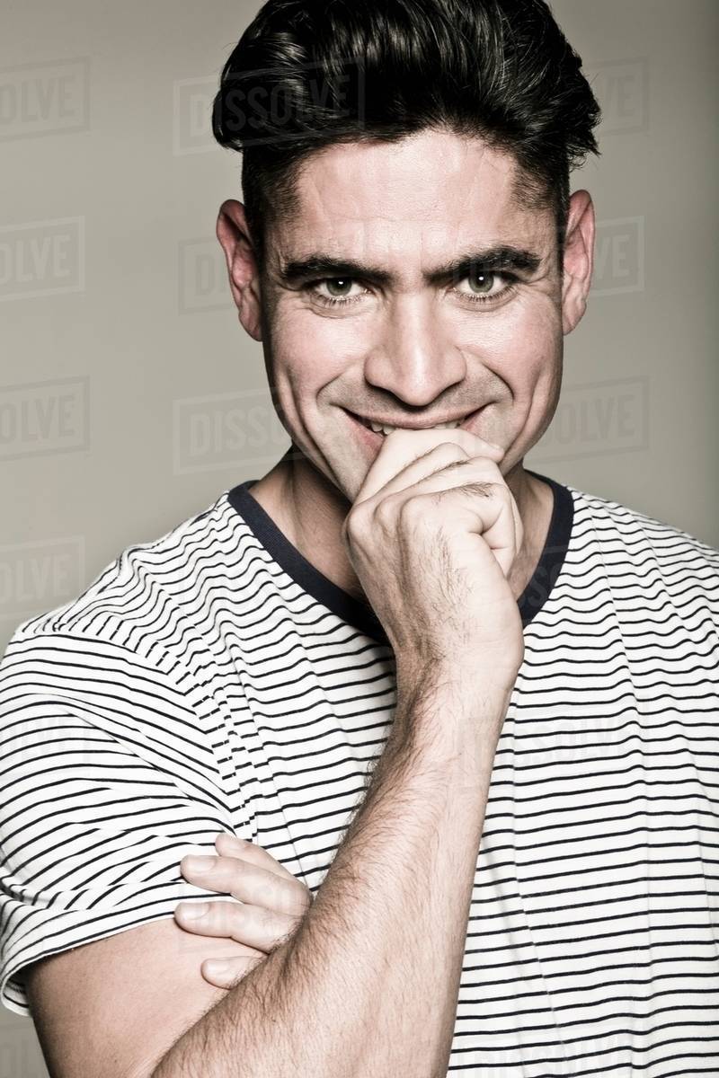 Smiling man biting his finger - Stock Photo - Dissolve