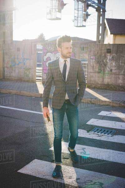 Stylish young man walking on pedestrian crossing - Stock Photo - Dissolve