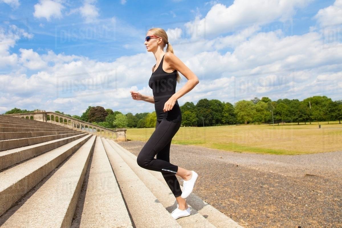Woman jogging up steps - Stock Photo - Dissolve