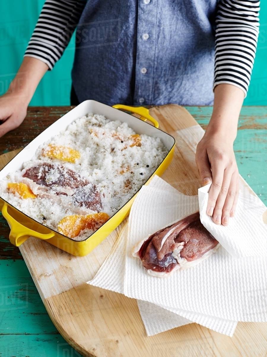 Woman preparing duck prosciutto step 2, drying salted duck breasts ...