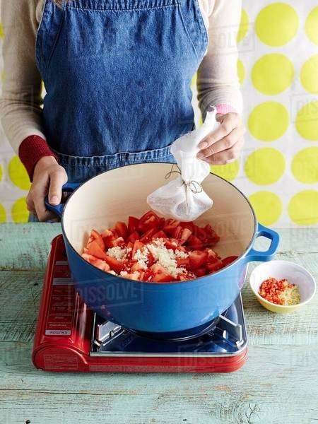 Woman preparing tomato ketchup recipe step 1, chopped tomatoes and ...