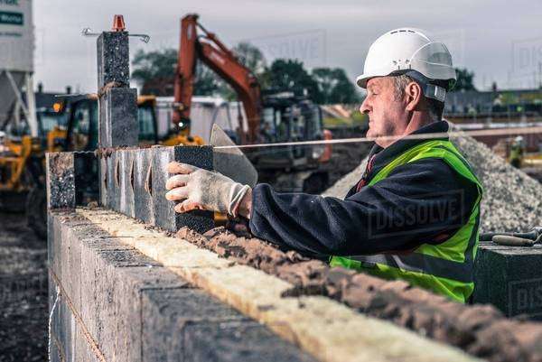 Workers laying bricks on construction site - Stock Photo - Dissolve