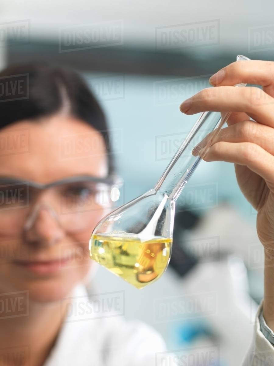 Chemist looking at solution in flask during research experiment ...