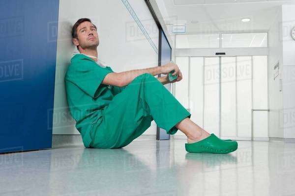 Doctor in scrubs, resting on the floor - Royalty-free Stock Photo ...