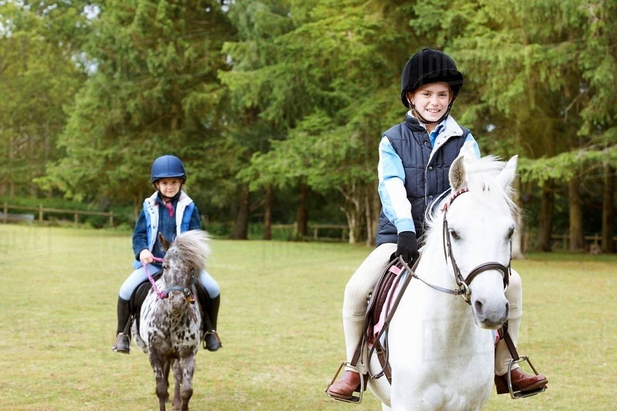 Two girls riding their ponies - Royalty-free Stock Photo | Dissolve