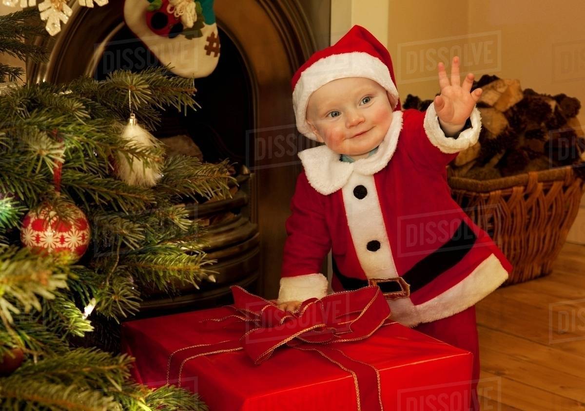 A baby santa standing next to a present - Royalty-free Stock Photo ...