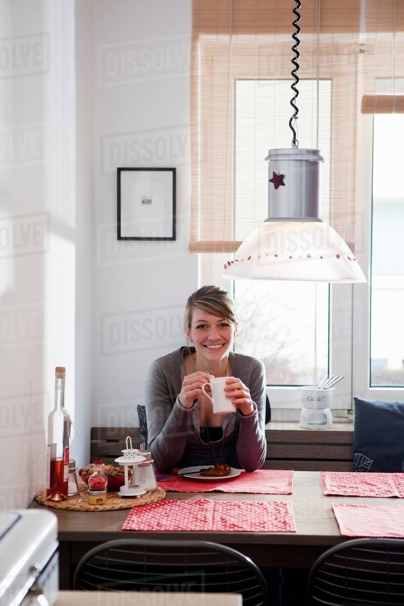 Woman sitting in kitchen - Stock Photo - Dissolve