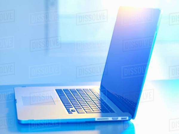Side view of open laptop on desk, sunlight coming through window ...