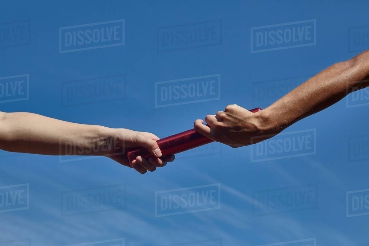 Hands of female relay runners passing baton against blue sky - Royalty ...