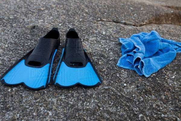 Blue swimming flippers and towel on beach - Stock Photo - Dissolve