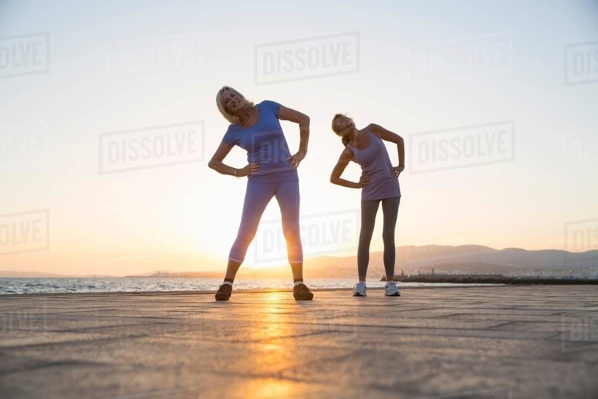 Women stretching by beach - Stock Photo - Dissolve