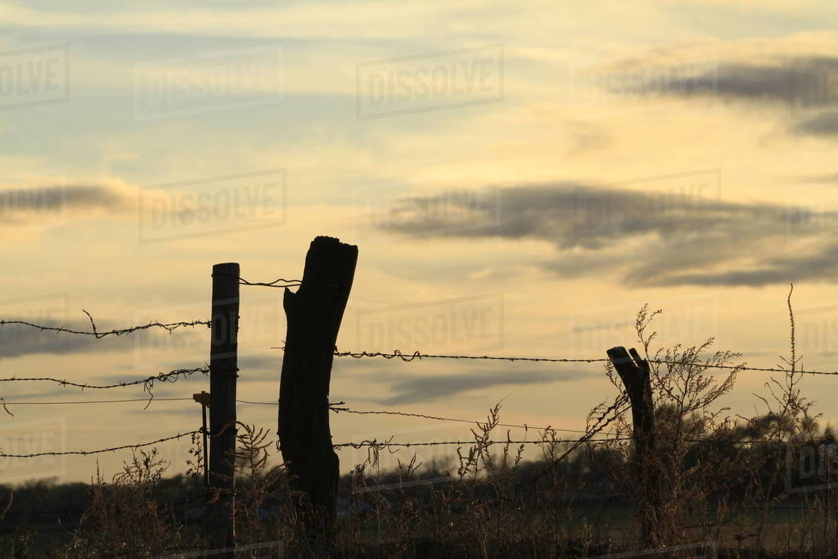 Kansas Sunset with a colorful Sky with clouds and a fence silhouette ...