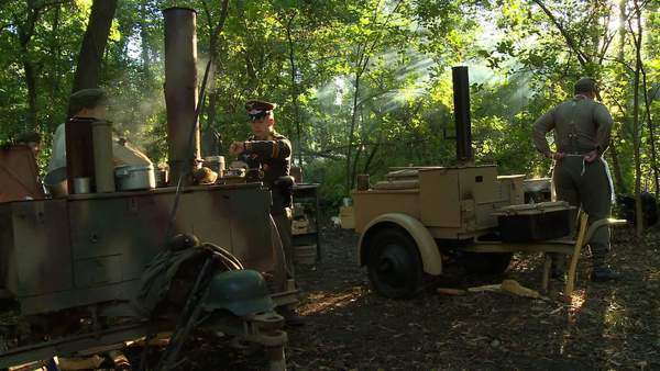 An officer checks his watch as the camp cooks prepare breakfast in an ...