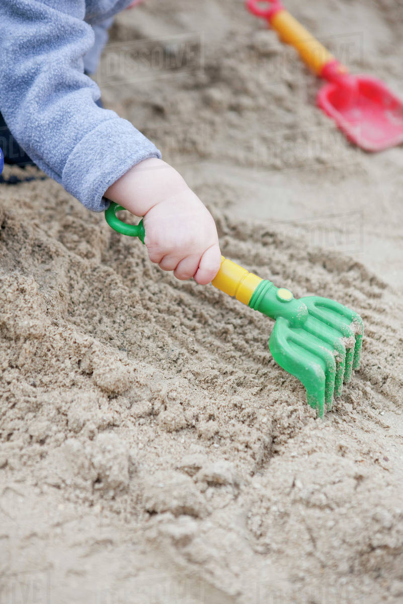 Toddler raking sand, cropped - Royalty-free Stock Photo | Dissolve