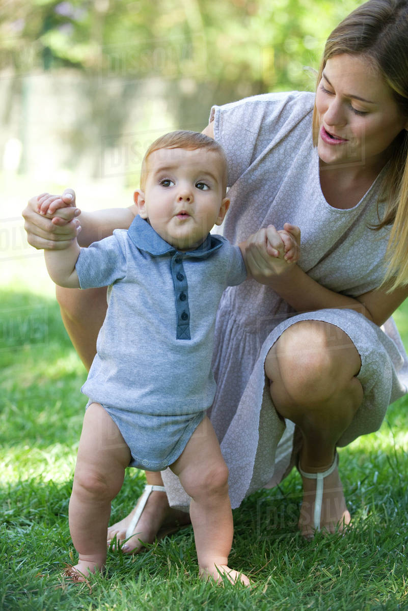 Mother helping baby stand outdoors - Royalty-free Stock Photo | Dissolve