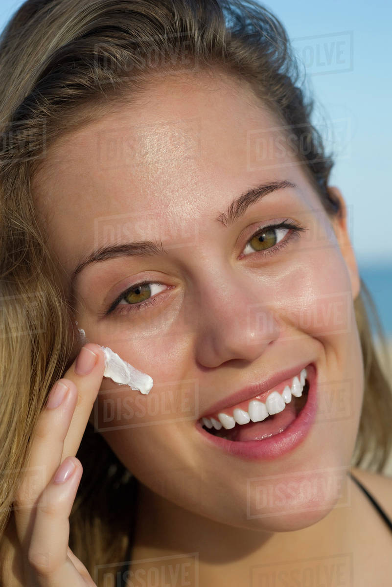 Woman applying sunscreen, portrait - Royalty-free Stock Photo | Dissolve