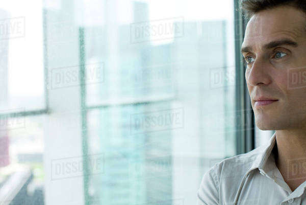 Man looking out of window - Stock Photo - Dissolve