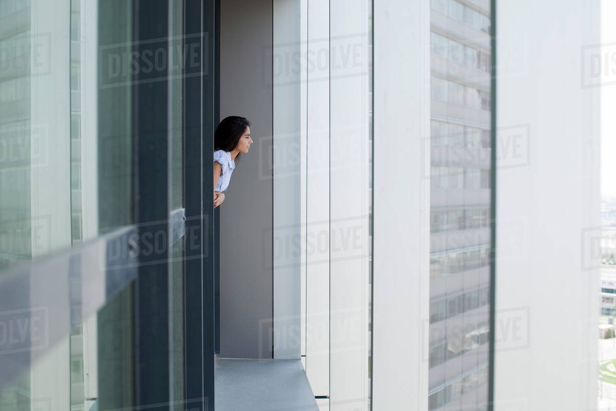 Woman leaning out of window looking at view - Stock Photo - Dissolve