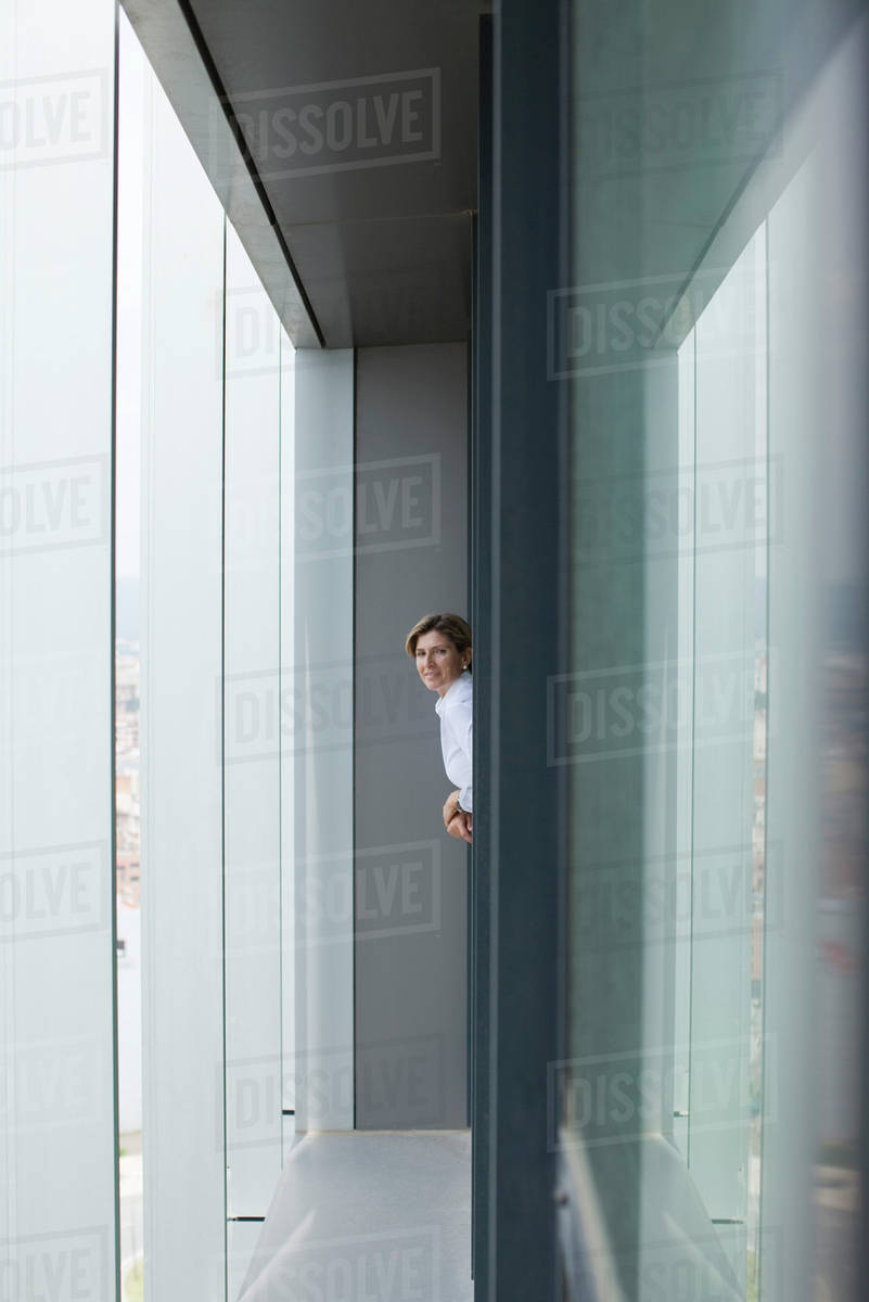 Woman leaning out of office window - Stock Photo - Dissolve