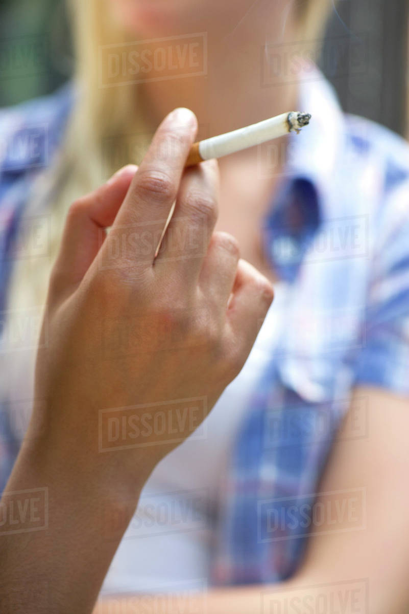 Woman's hand holding lit cigarette - Royalty-free Stock Photo | Dissolve
