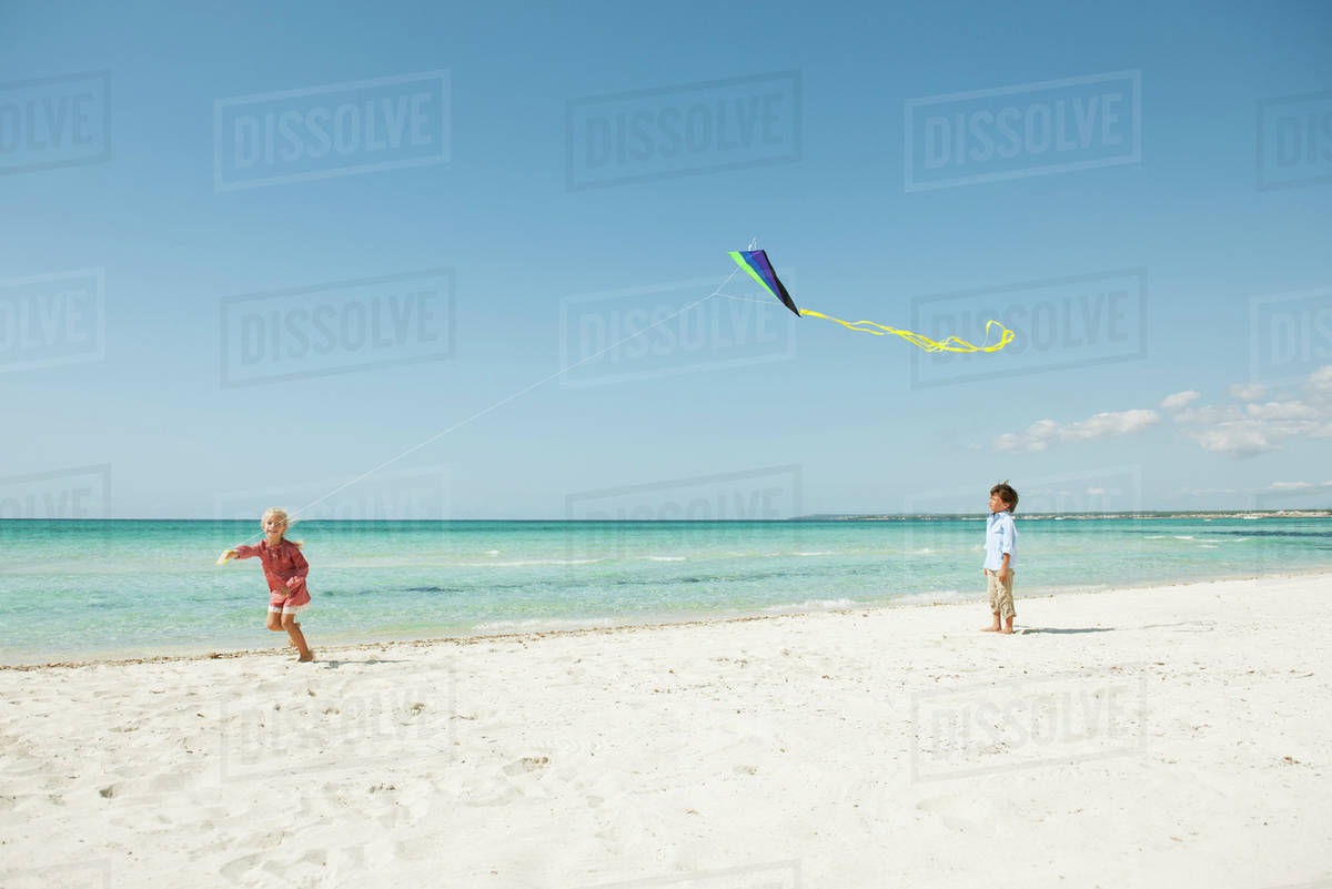 Boy watching girl flying kite - Royalty-free Stock Photo | Dissolve