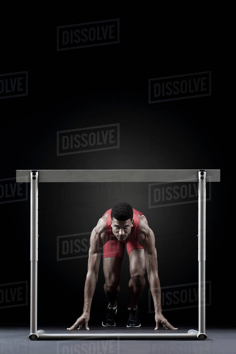 Male athlete at starting position in front of hurdle - Royalty-free ...