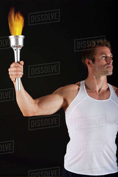 Male athlete holding up torch - Royalty-free Stock Photo | Dissolve